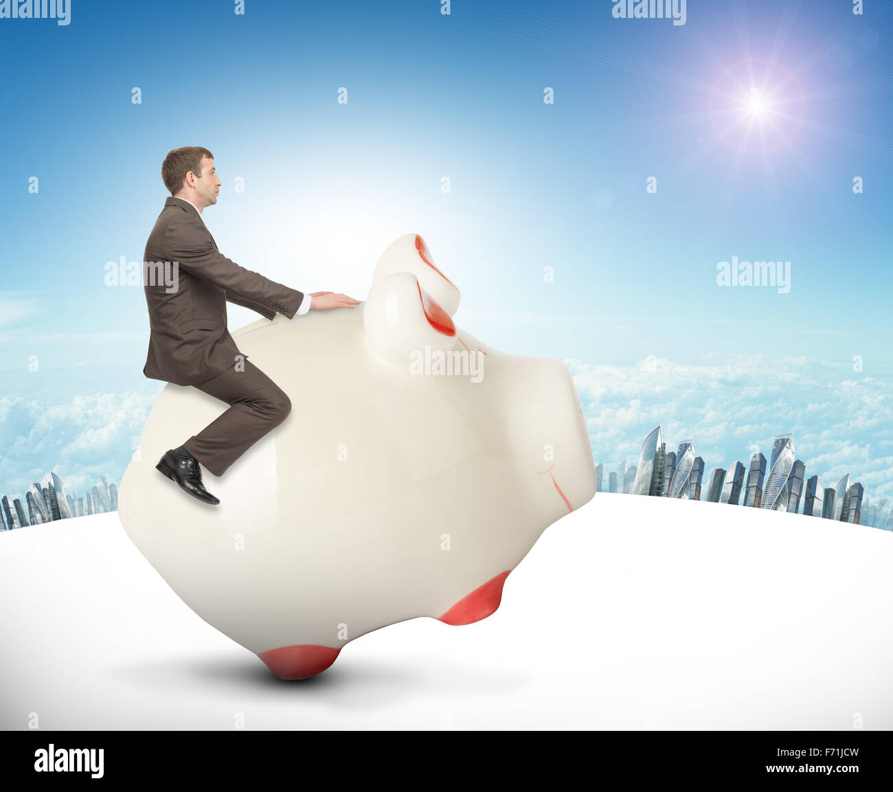 Man sitting on white piggy bank, side view Stock Photo - Alamy