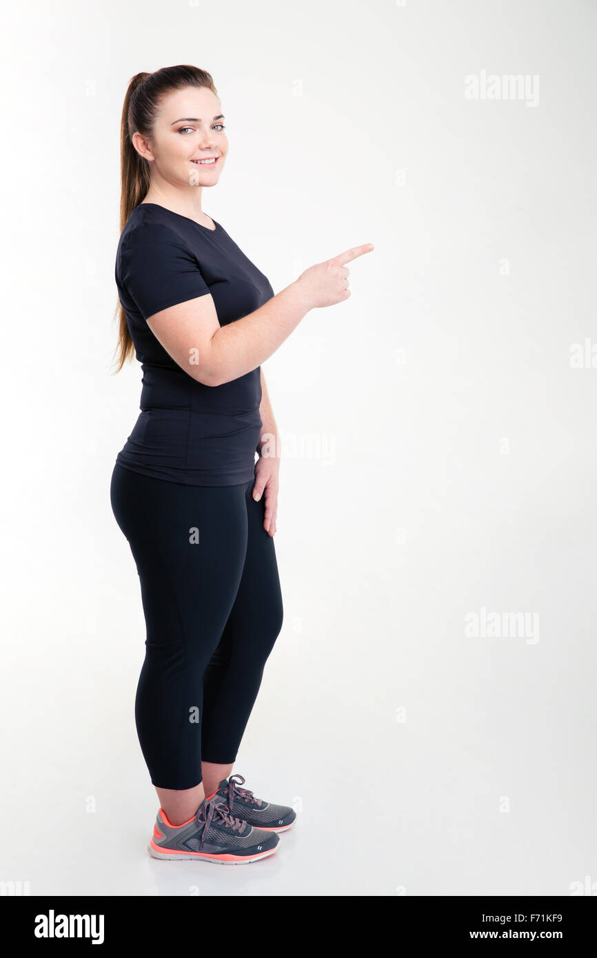 Full length portrait of a sports fat woman pointing finger away ...