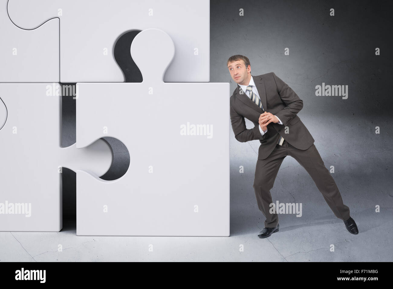 Man in suit pushing puzzle piece Stock Photo - Alamy