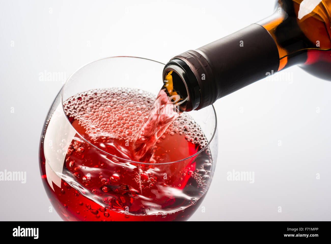 bottle pouring red wine into glass on white background Stock Photo - Alamy