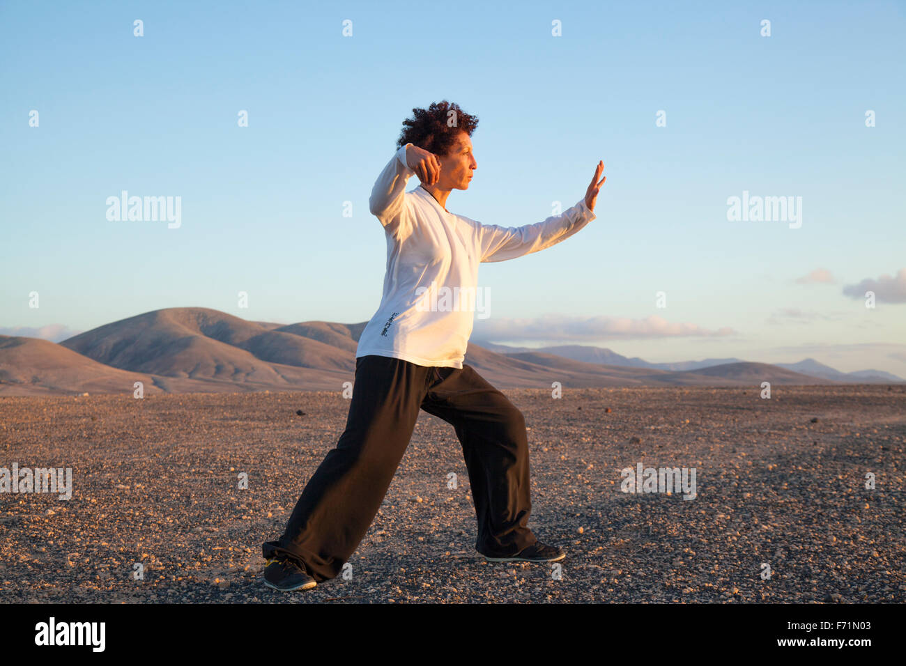 young woamn performs tai chi moves at sunset, background of Northern ...