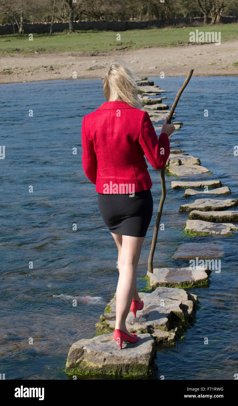 Woman holding a stick to test depth of water crossing a river using ...