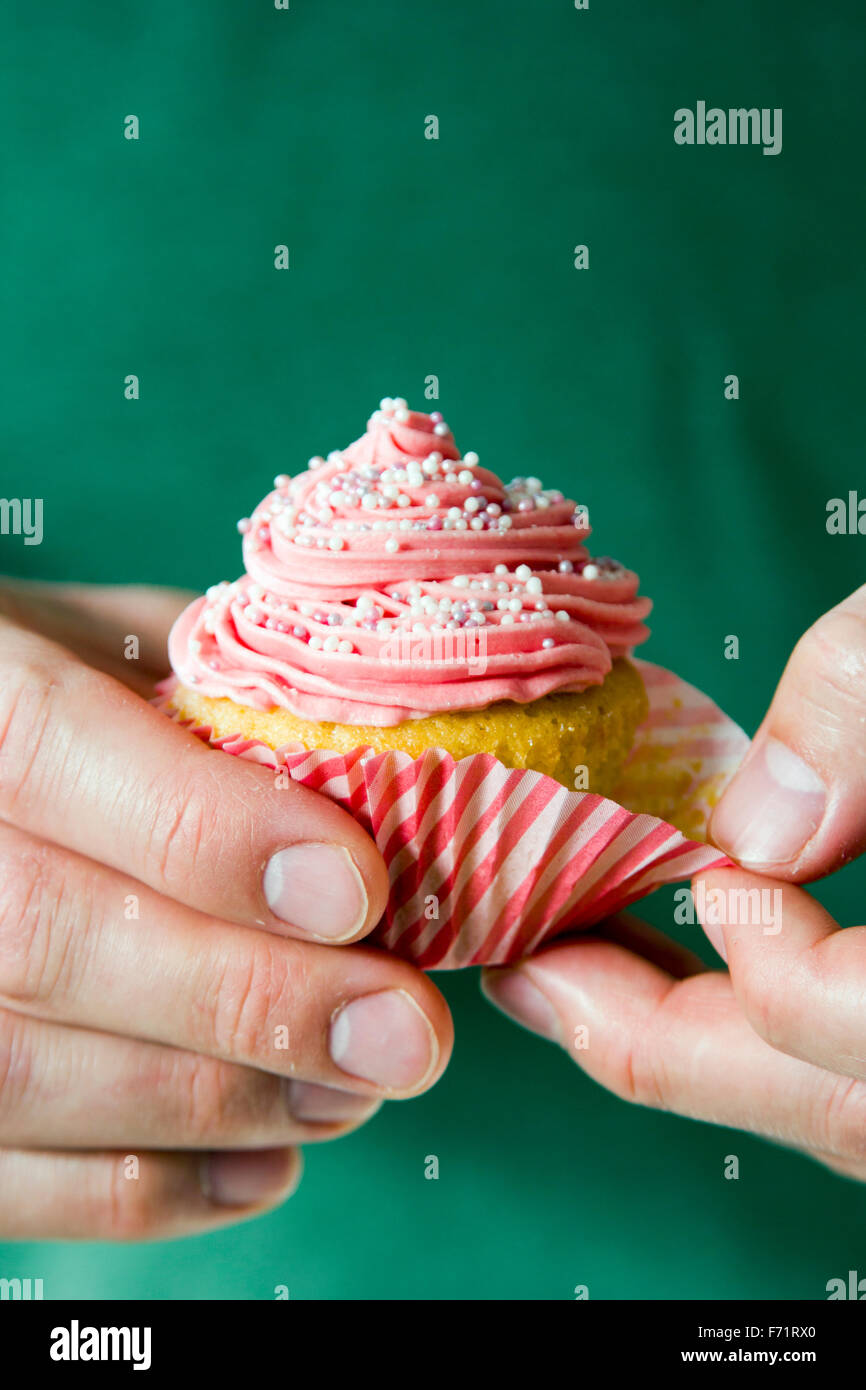 Pink frosted cupcake being unwrapped Stock Photo - Alamy