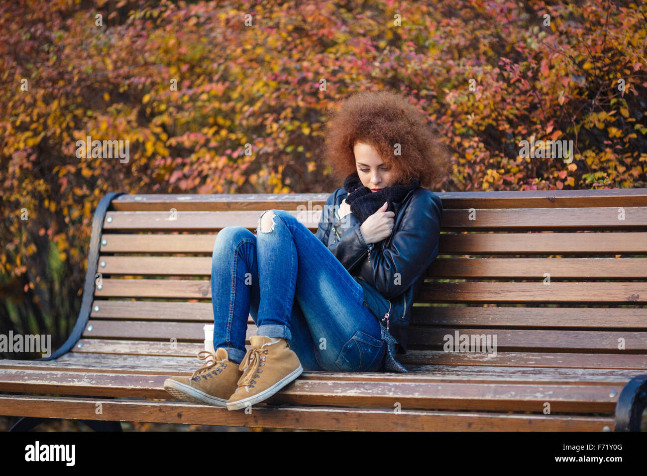 Portrait of a young sad woman sitting on the bench in autumn park Stock ...