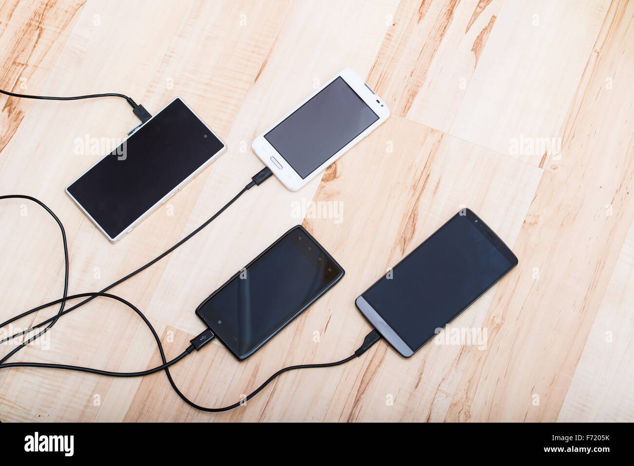 four smartphones connected to chargers Stock Photo - Alamy