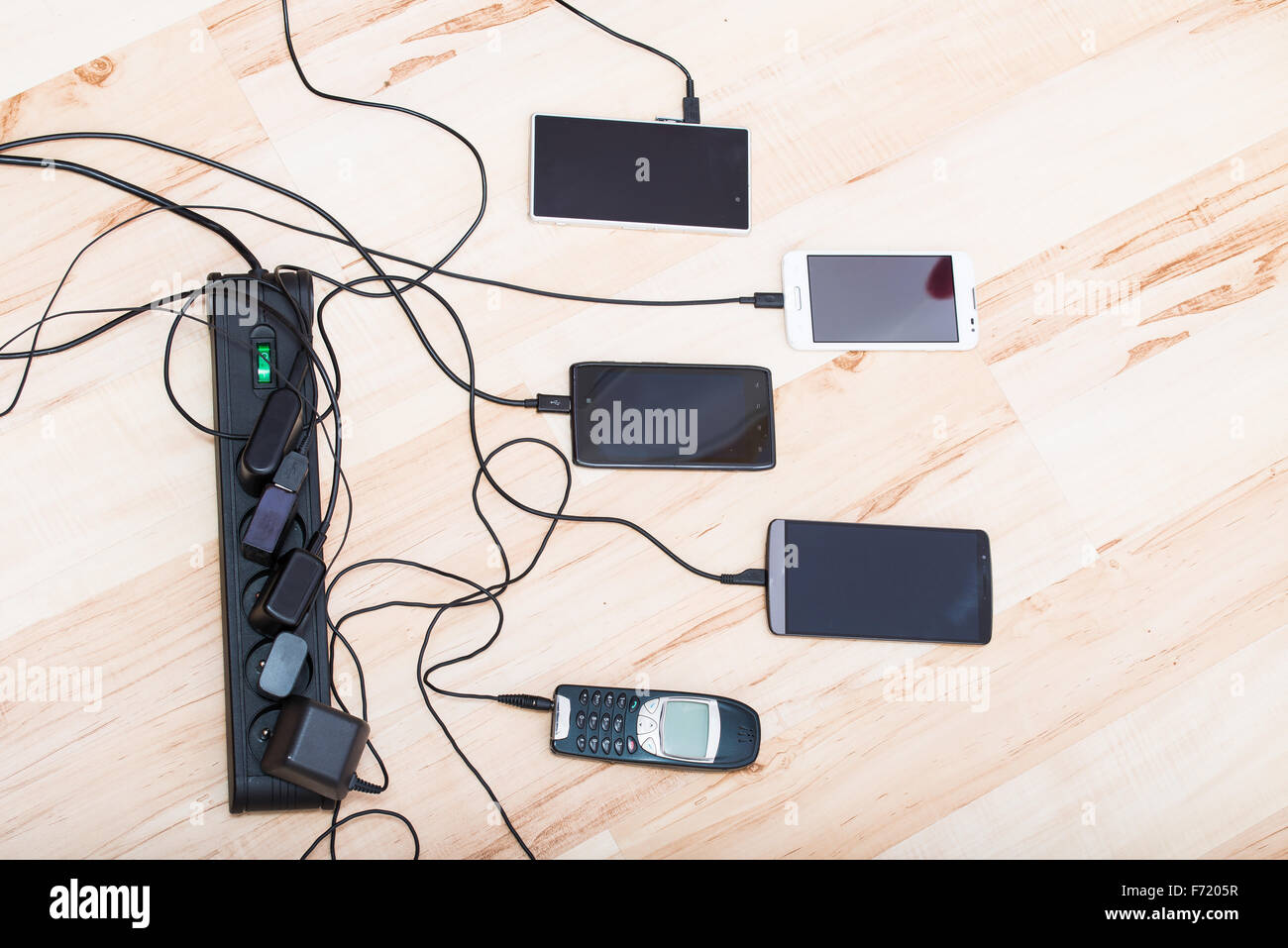 four smartphones and one classic phone connected to chargers Stock ...