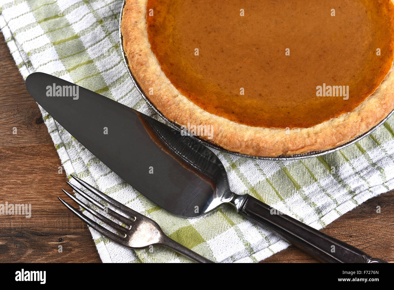 High angle view of a pumpkin pie, server and fork. The dessert is part ...