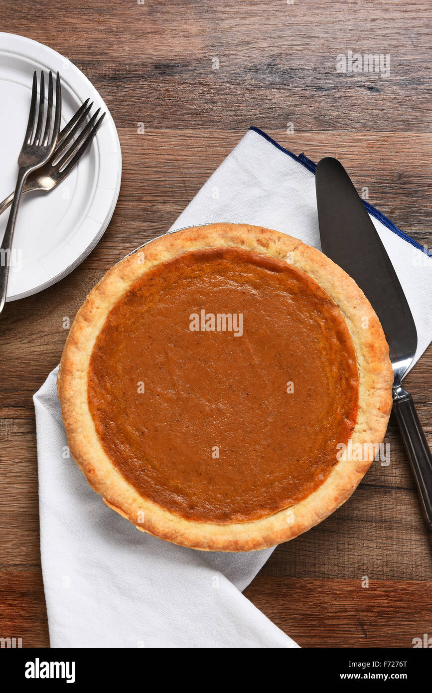 High angle vertical view of a pumpkin pie, server with plates and forks ...