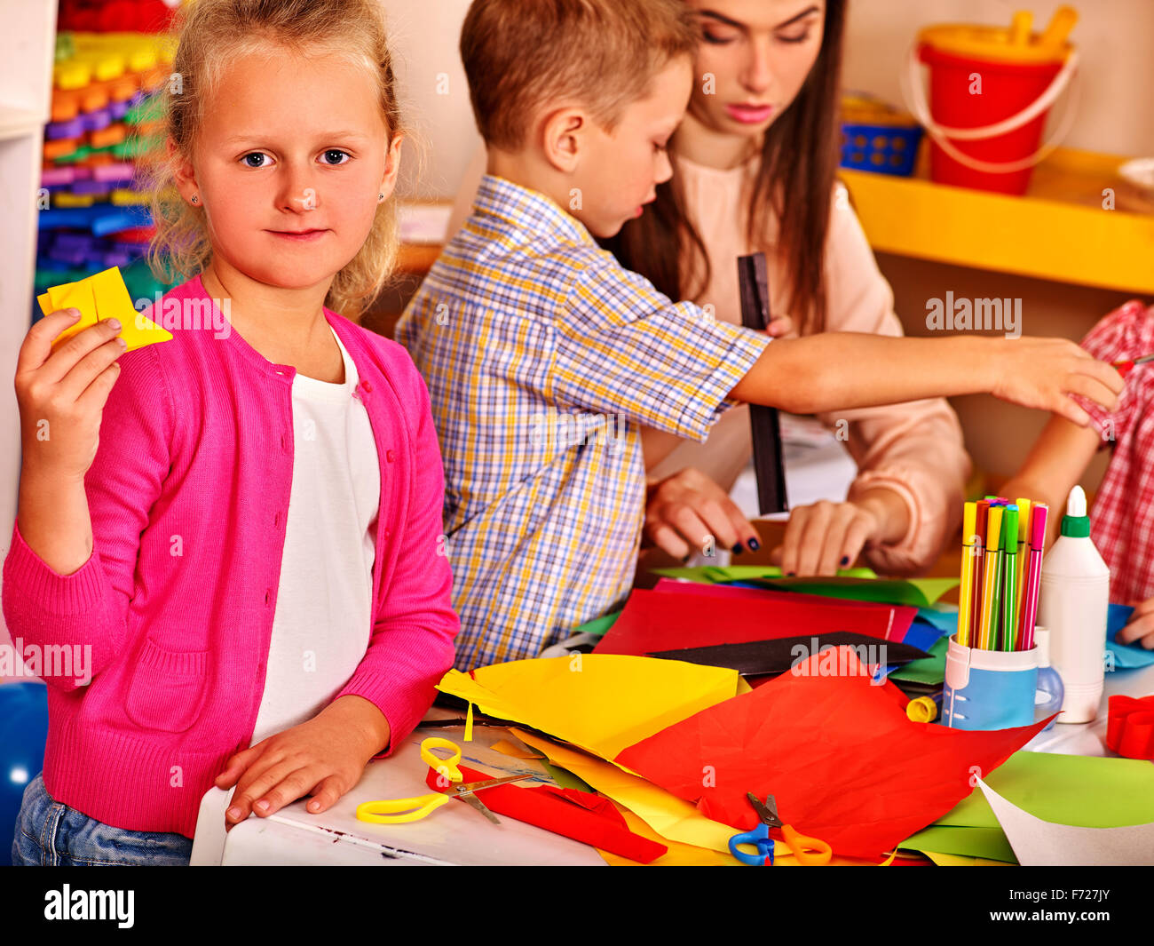 Kids holding colored paper on table in kindergarten Stock Photo - Alamy