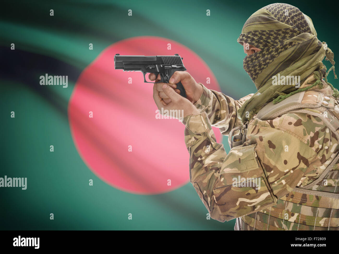 Male in muslim keffiyeh with gun in hand and national flag on ...