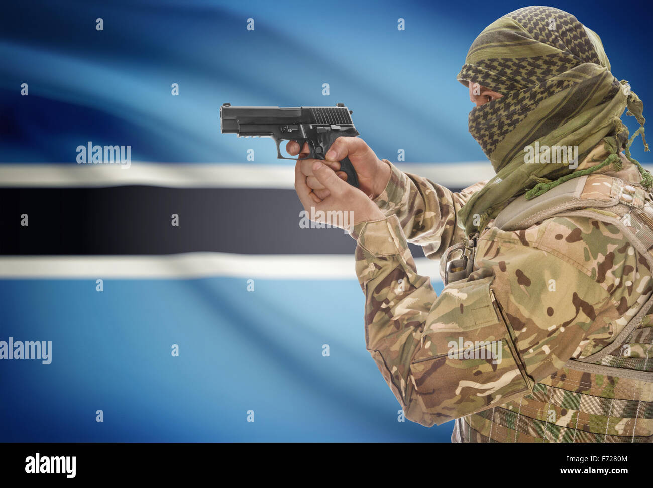 Male in muslim keffiyeh with gun in hand and national flag on ...