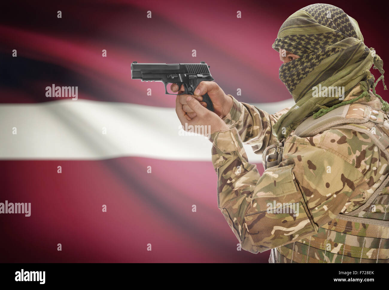 Male in muslim keffiyeh with gun in hand and national flag on ...