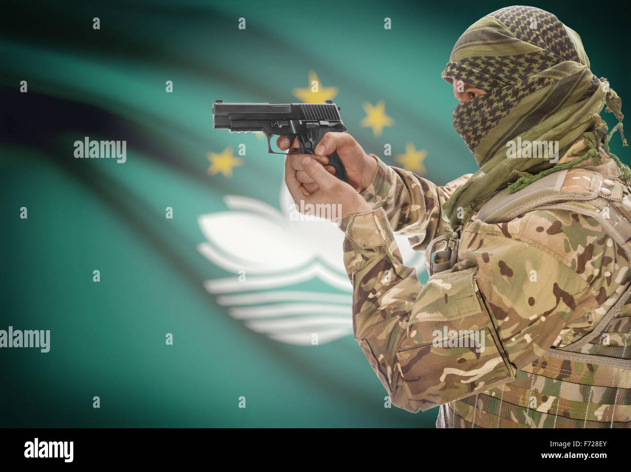 Male in muslim keffiyeh with gun in hand and national flag on ...