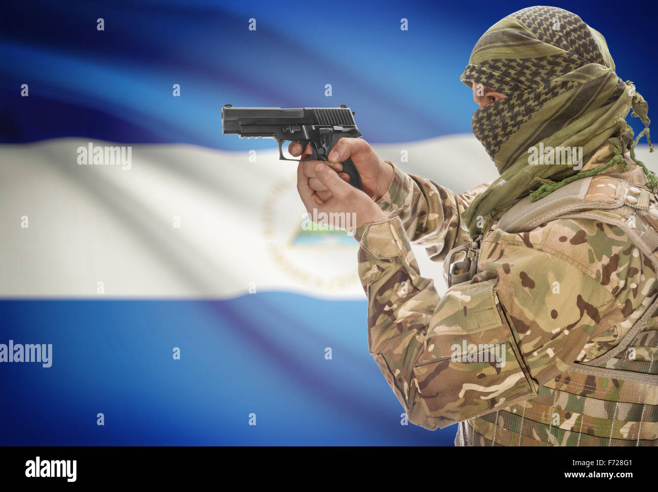 Male in muslim keffiyeh with gun in hand and national flag on ...