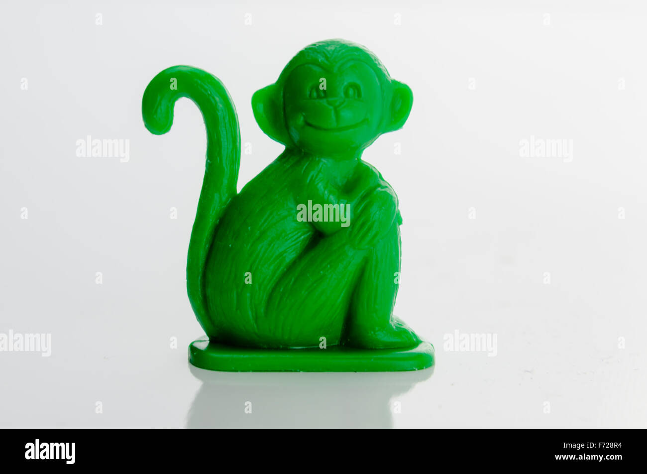 A green plastic monkey against a white background Stock Photo - Alamy