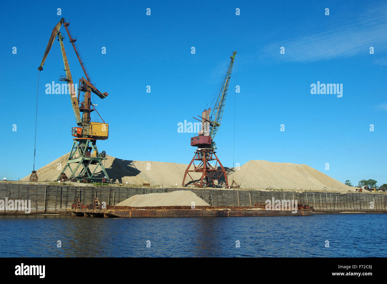 Loading sand with the help of a crane on a barge on the water and sky ...