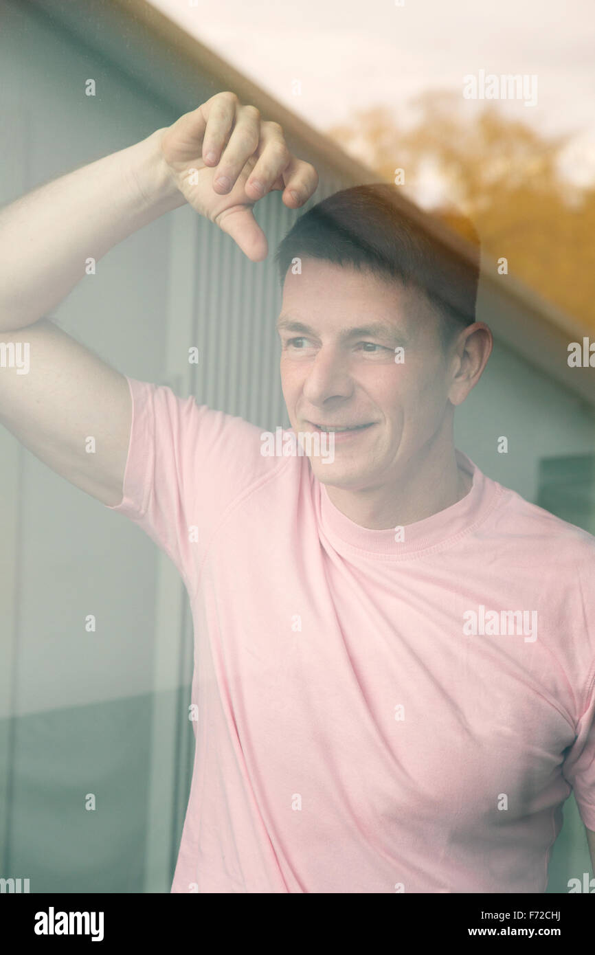 handsome man looking out of window and smiles Stock Photo - Alamy