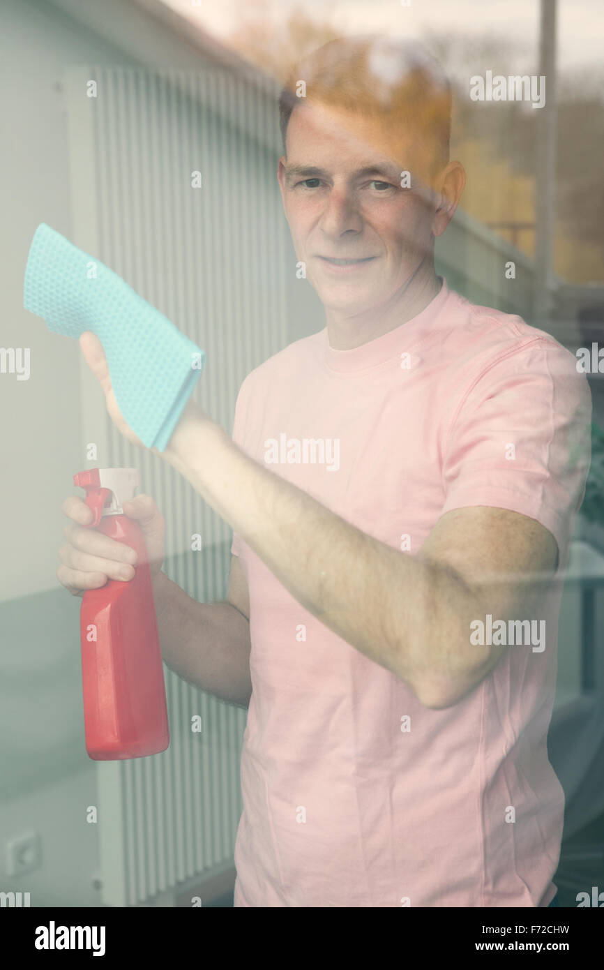 handsome man cleaning a window and smiles Stock Photo - Alamy