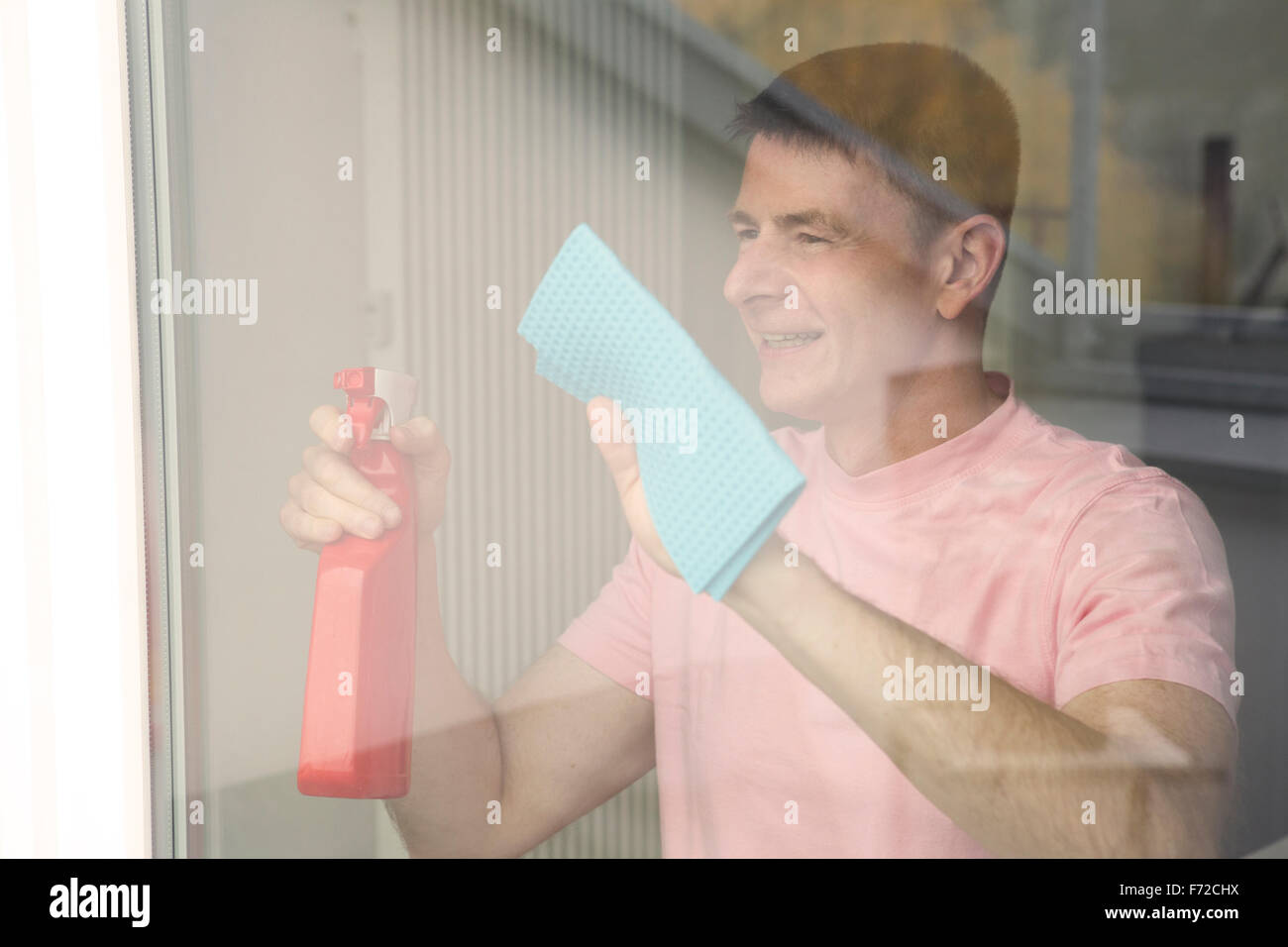 handsome man cleaning a window and smiles Stock Photo - Alamy