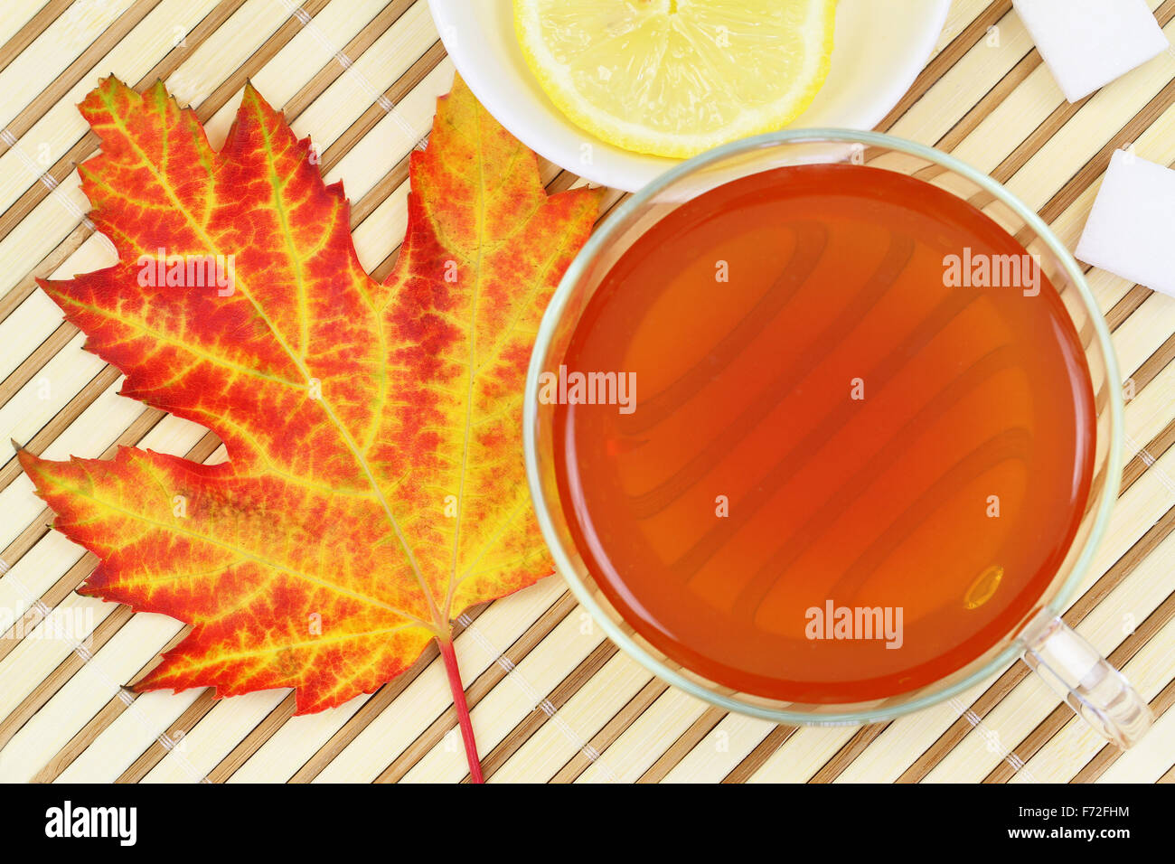 Red and yellow autumn leaf and cup of lemon tea Stock Photo - Alamy