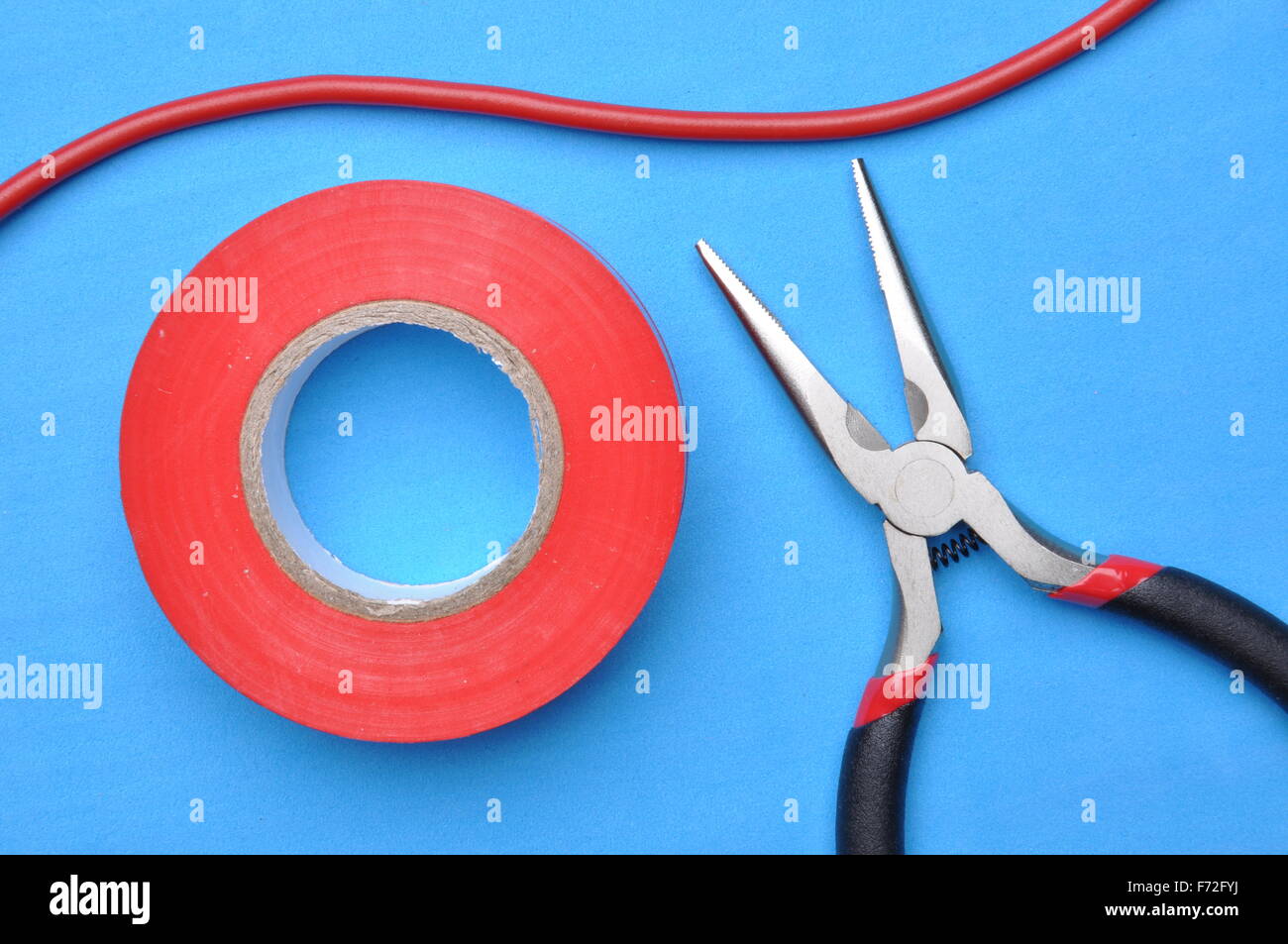 Tools for electrician pliers, insulation tape and cable on blue ...