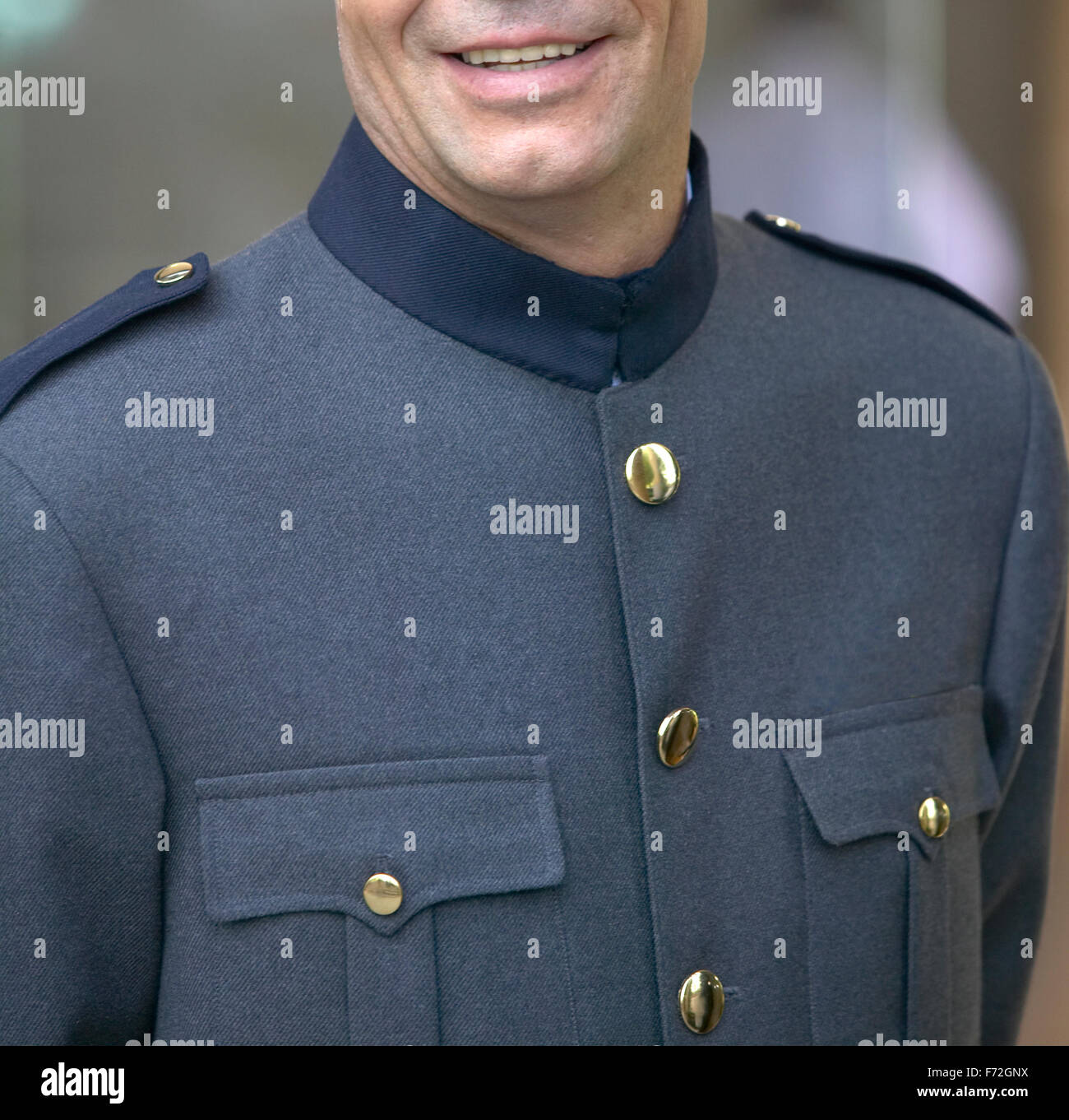 Smiley bellhop with grey uniform and golden buttons Stock Photo - Alamy