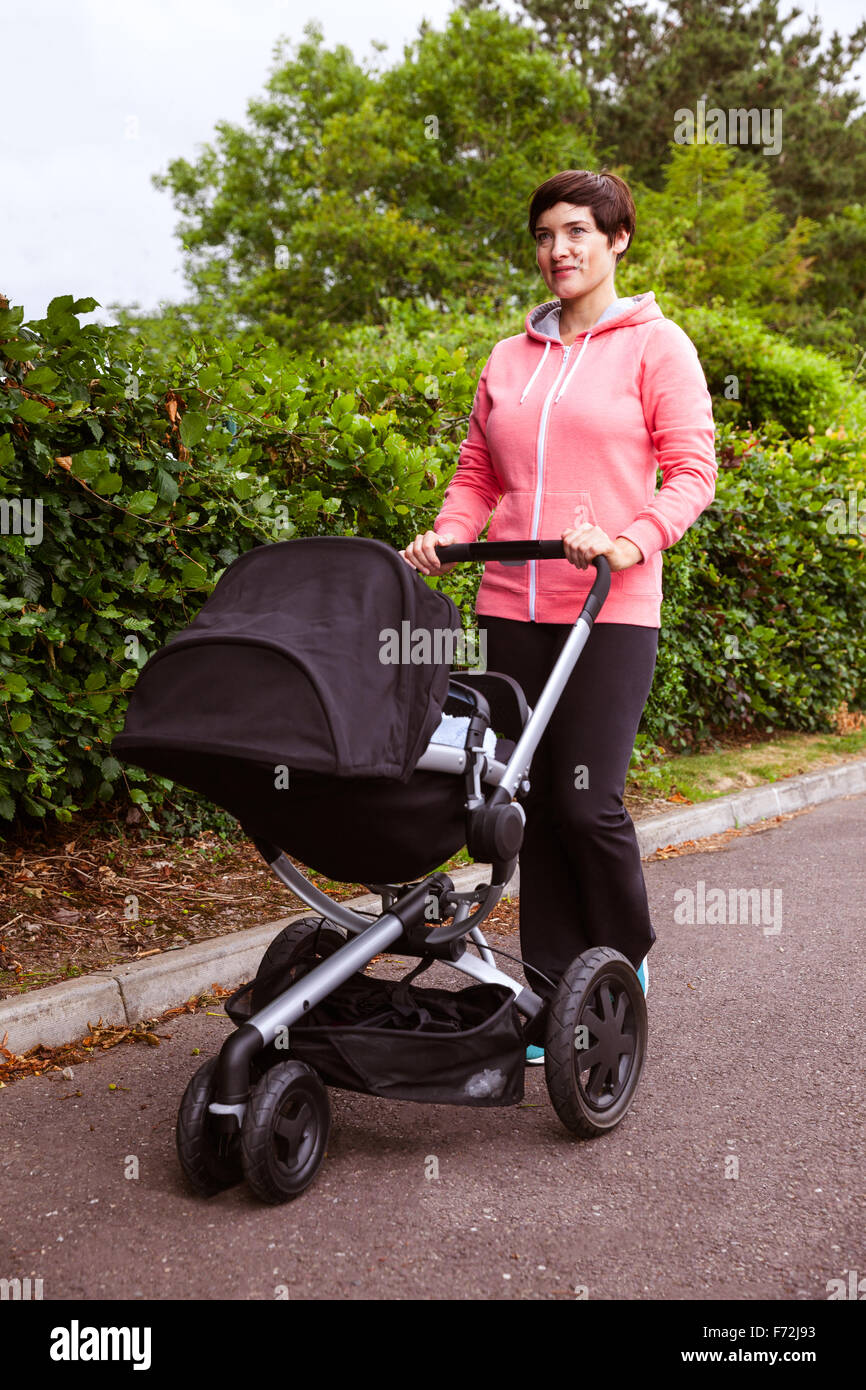 Mother walking and pushing pram Stock Photo - Alamy