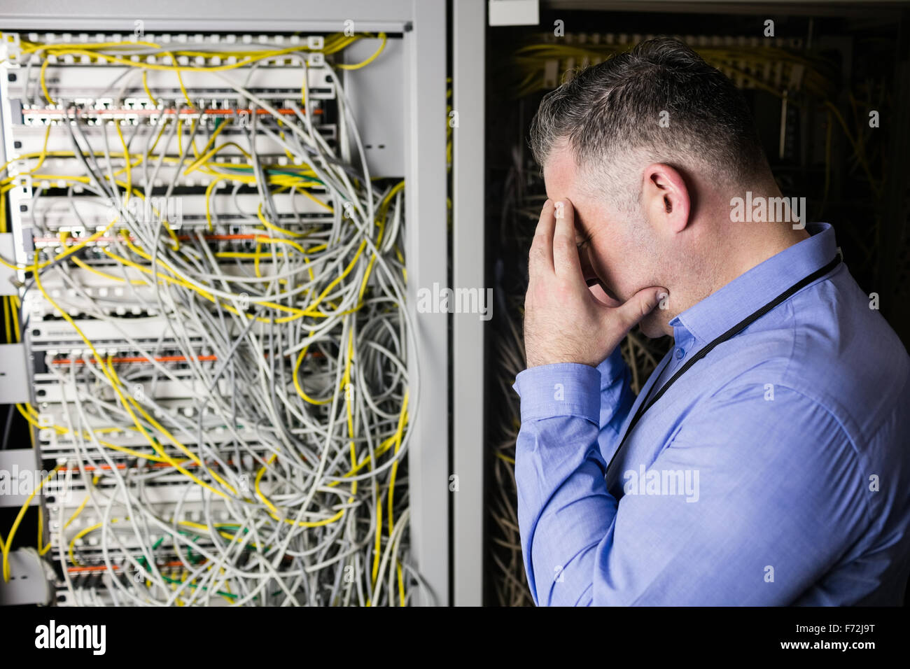 Stressed technician looking at open server locker Stock Photo - Alamy