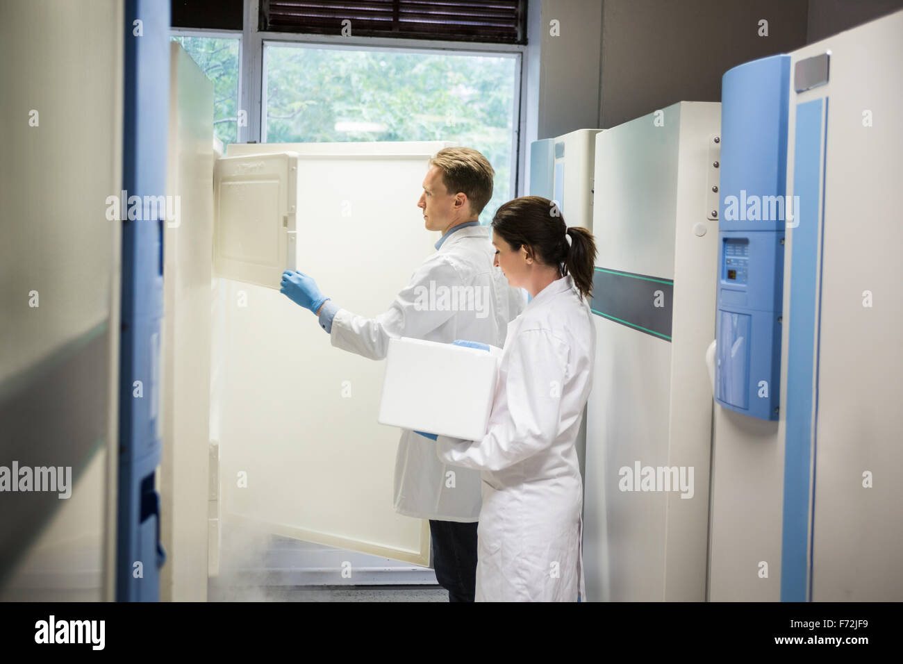 Two scientists using large fridge unit Stock Photo - Alamy