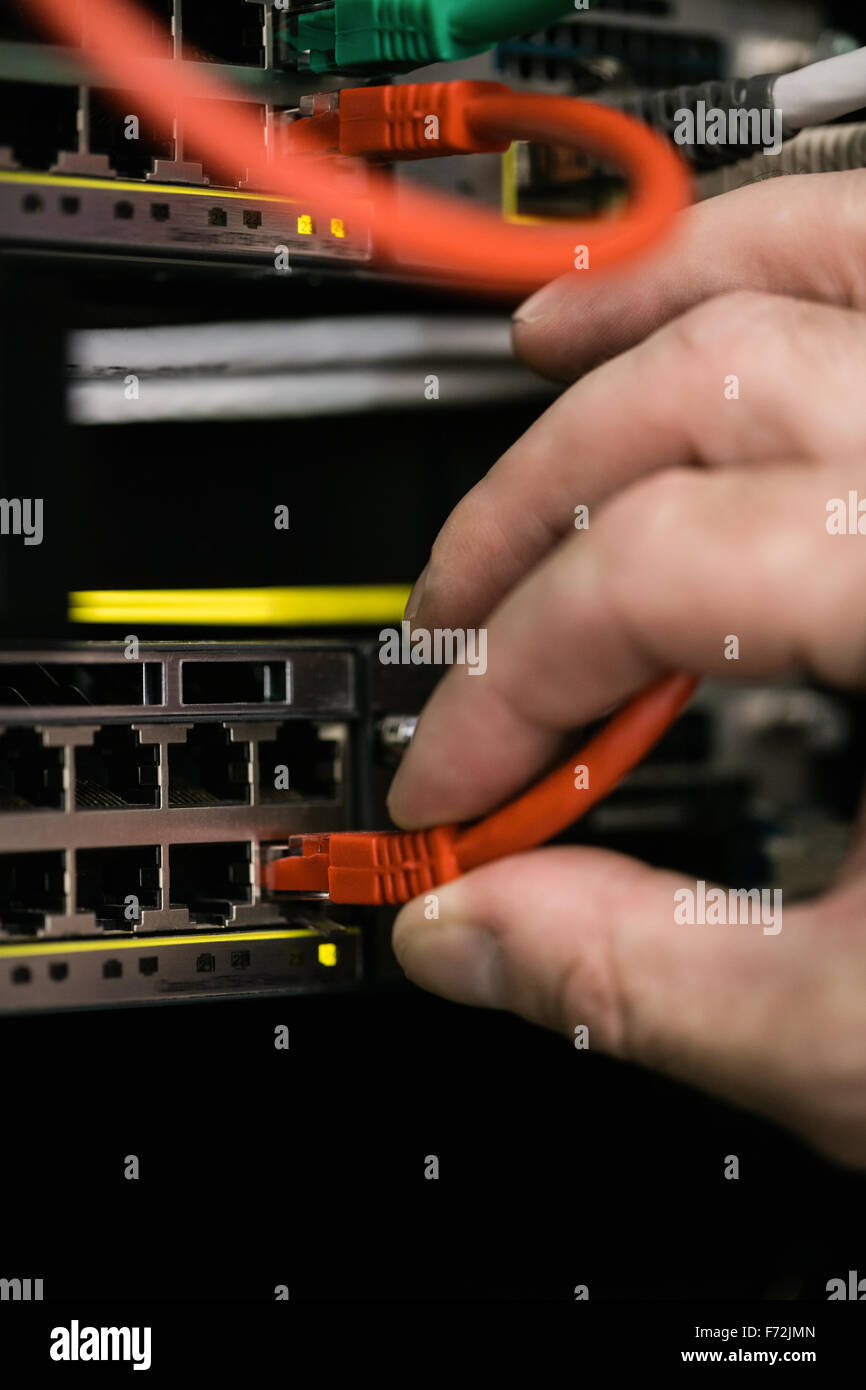Technician inserting wire to server Stock Photo - Alamy
