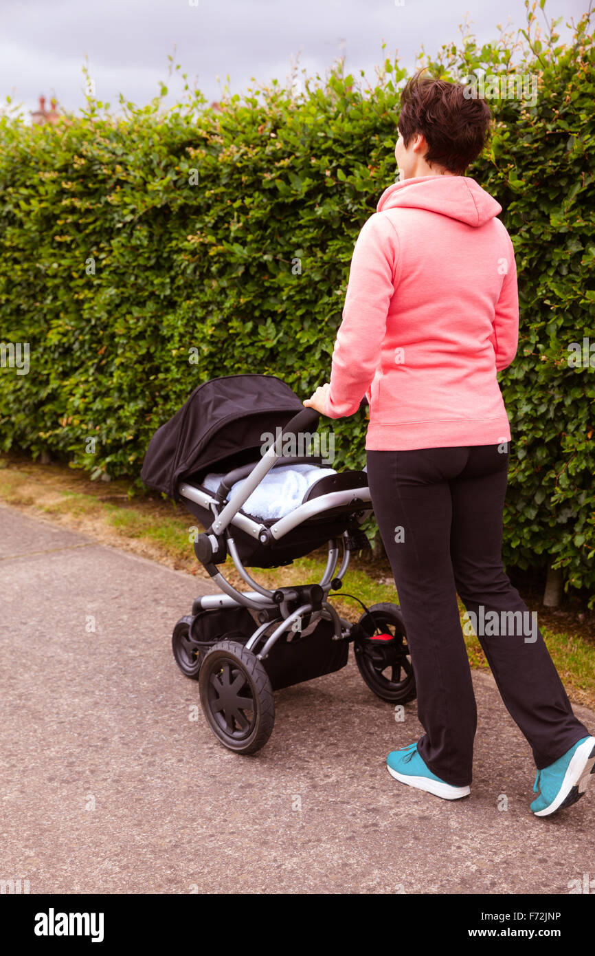 Mother walking and pushing pram Stock Photo - Alamy