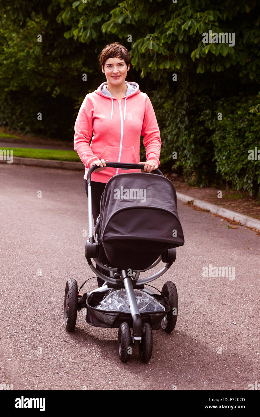 Mother walking and pushing pram Stock Photo - Alamy