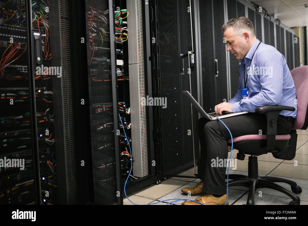 Technician using laptop in server room Stock Photo - Alamy