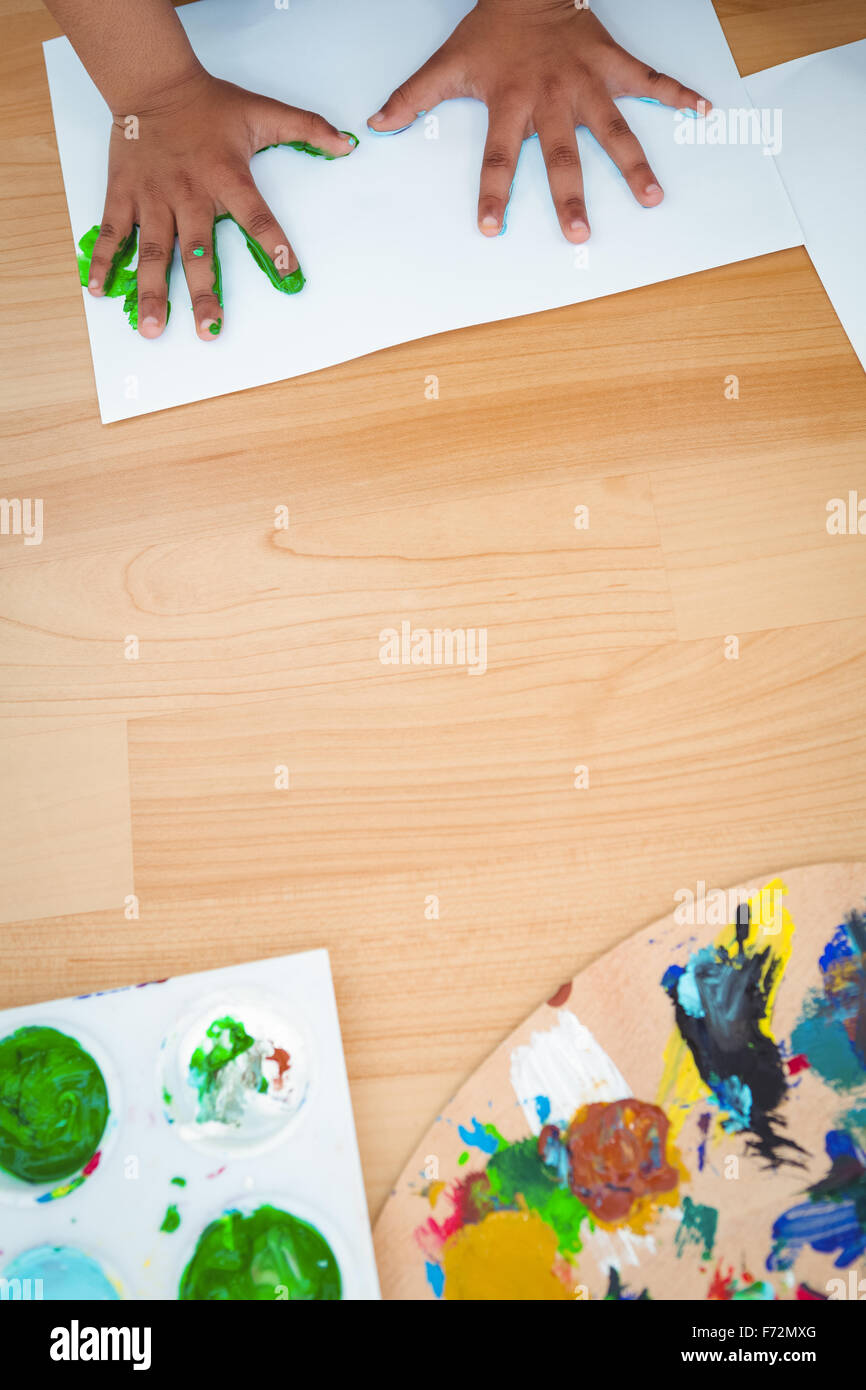Girl pressing paint covered hands on white paper Stock Photo - Alamy