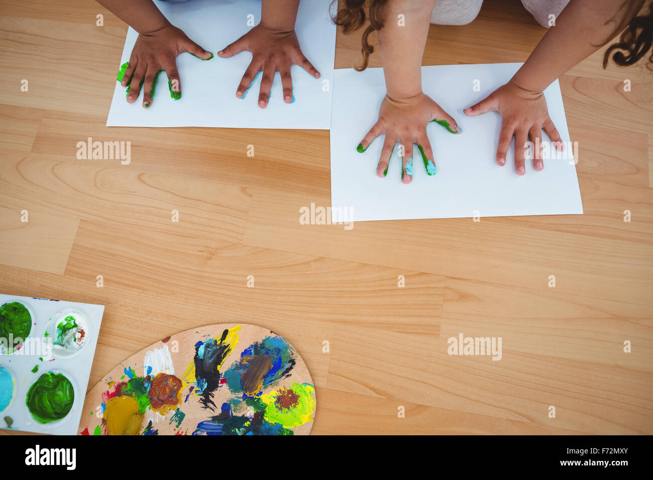 Girls pressing paint covered hands on white paper Stock Photo - Alamy