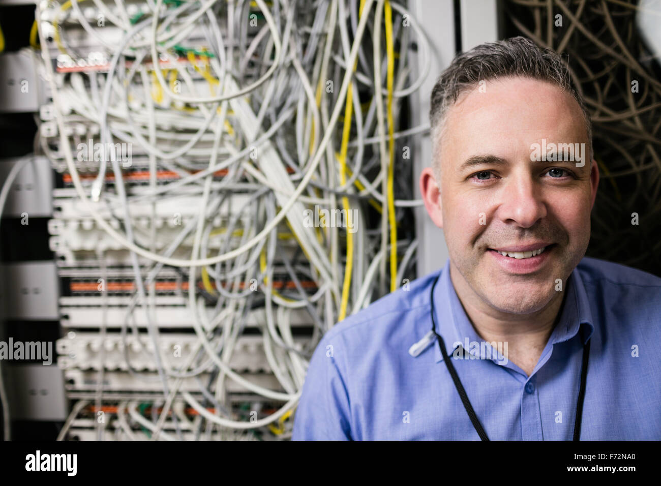 Technician smiling at camera beside server Stock Photo - Alamy