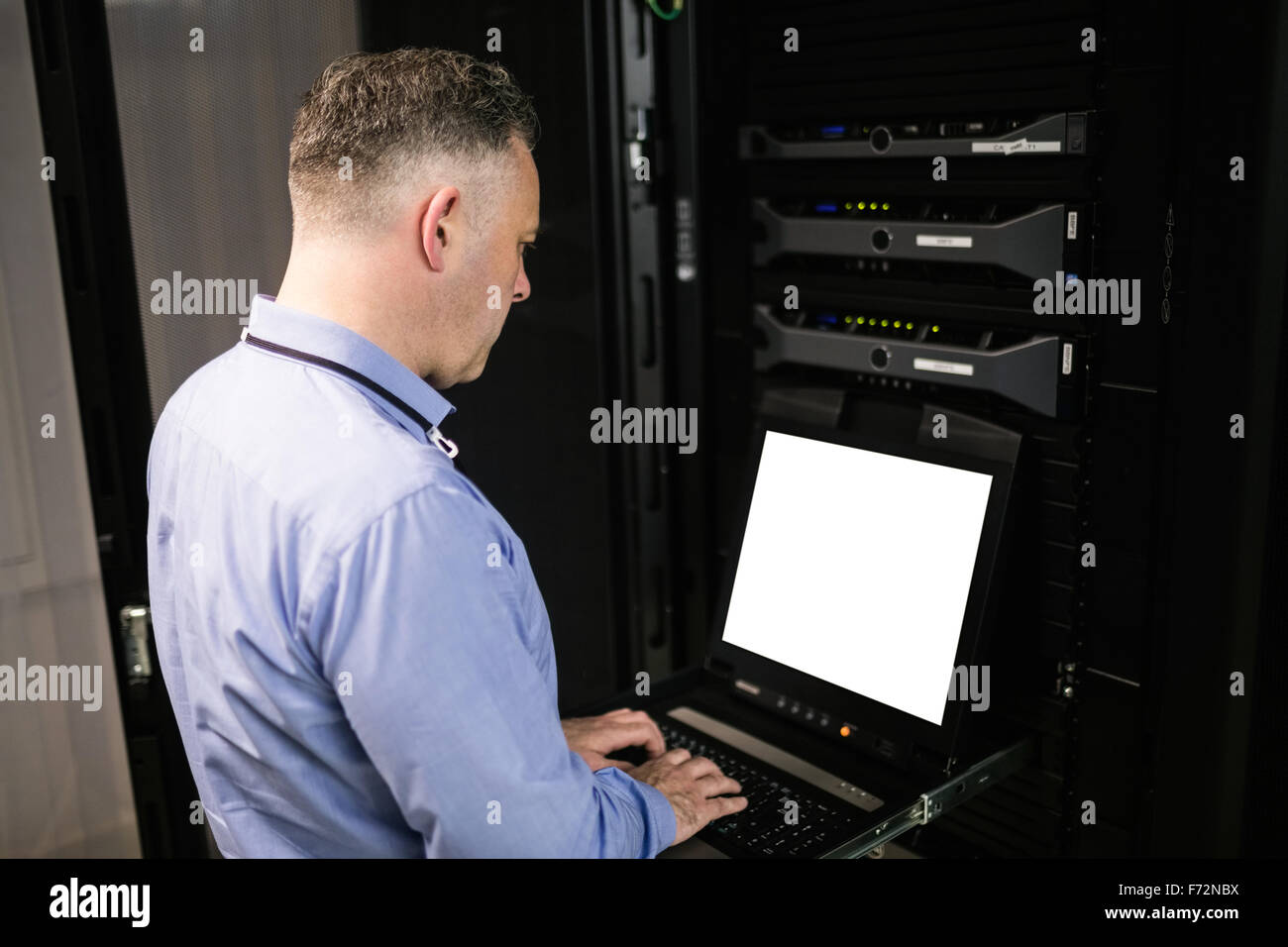 Technician using laptop in server room Stock Photo - Alamy