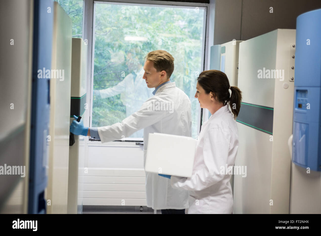 Two scientists using large fridge unit Stock Photo - Alamy
