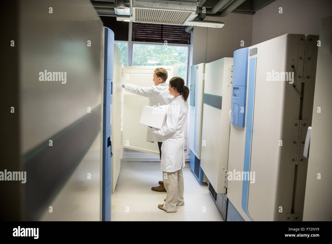 Two scientists using large fridge unit Stock Photo - Alamy