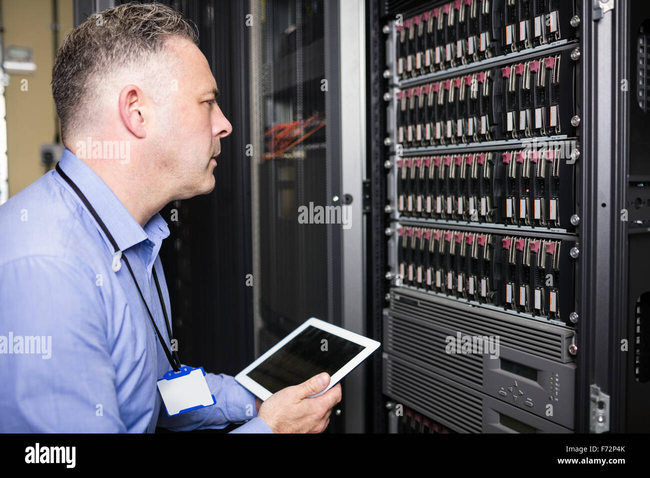 Technician using tablet pc while analysing server Stock Photo - Alamy