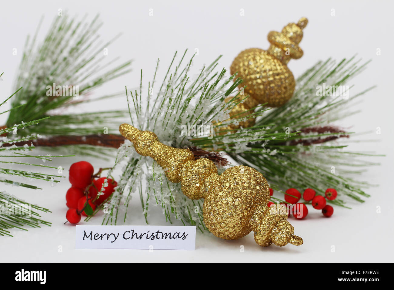 Merry Christmas card with golden baubles and pine covered with snow ...
