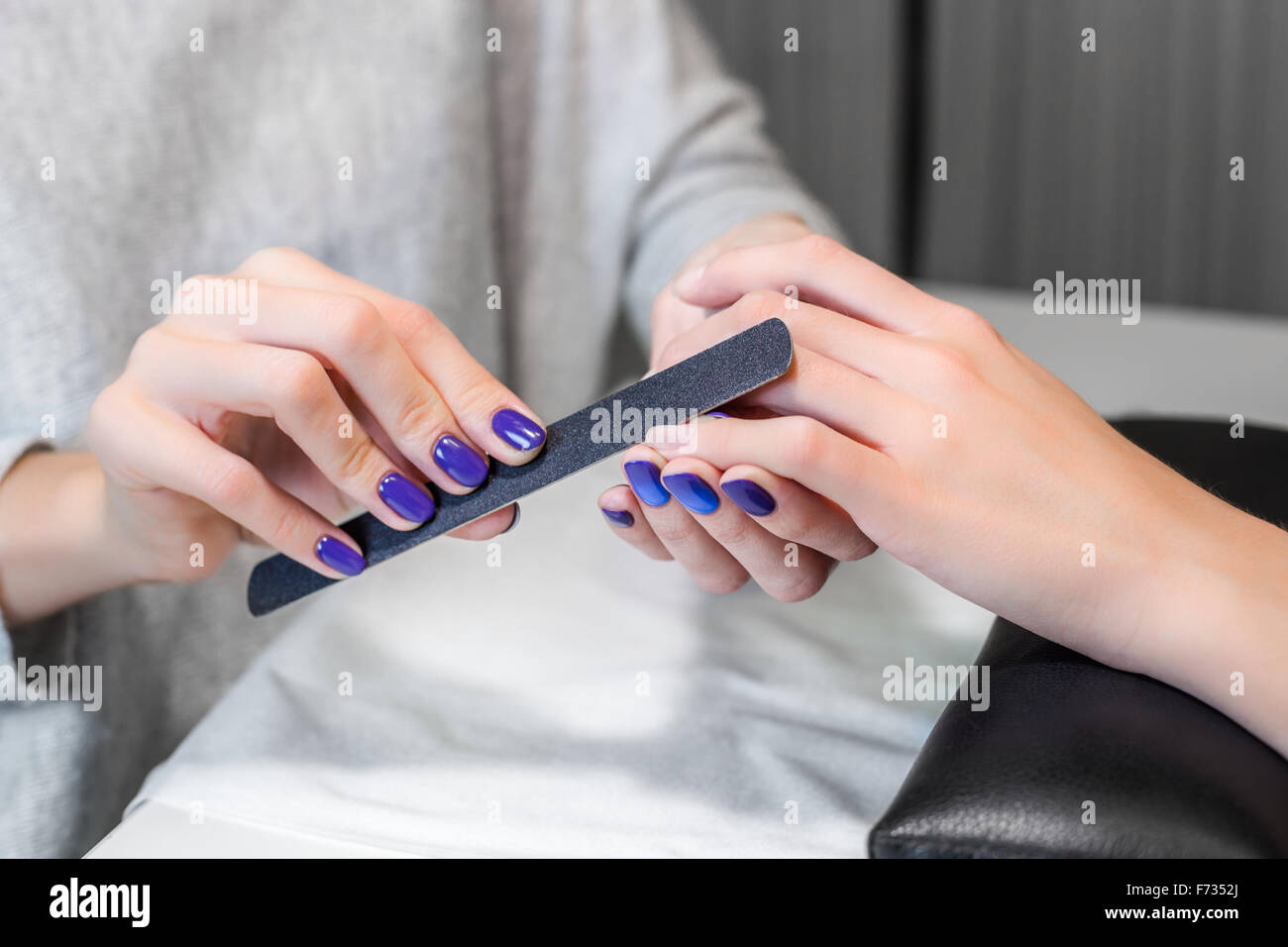 Manicurist filing client nail manicure in salon Stock Photo - Alamy