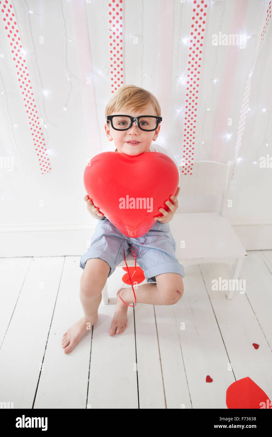 Young boy posing for a picture in a photographers studio, holding red ...