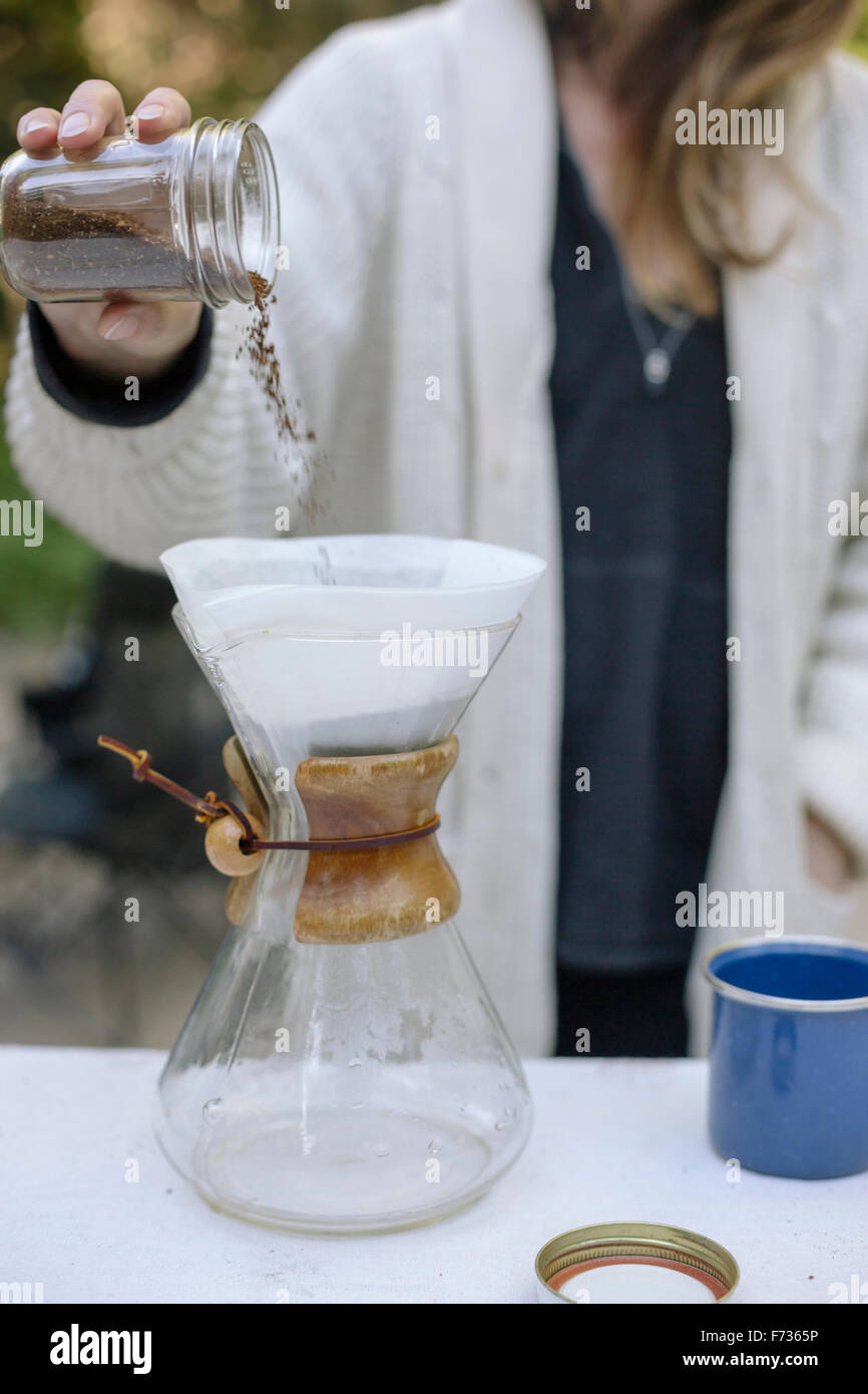 Woman pouring ground coffee from a jar into a glass coffee maker Stock ...