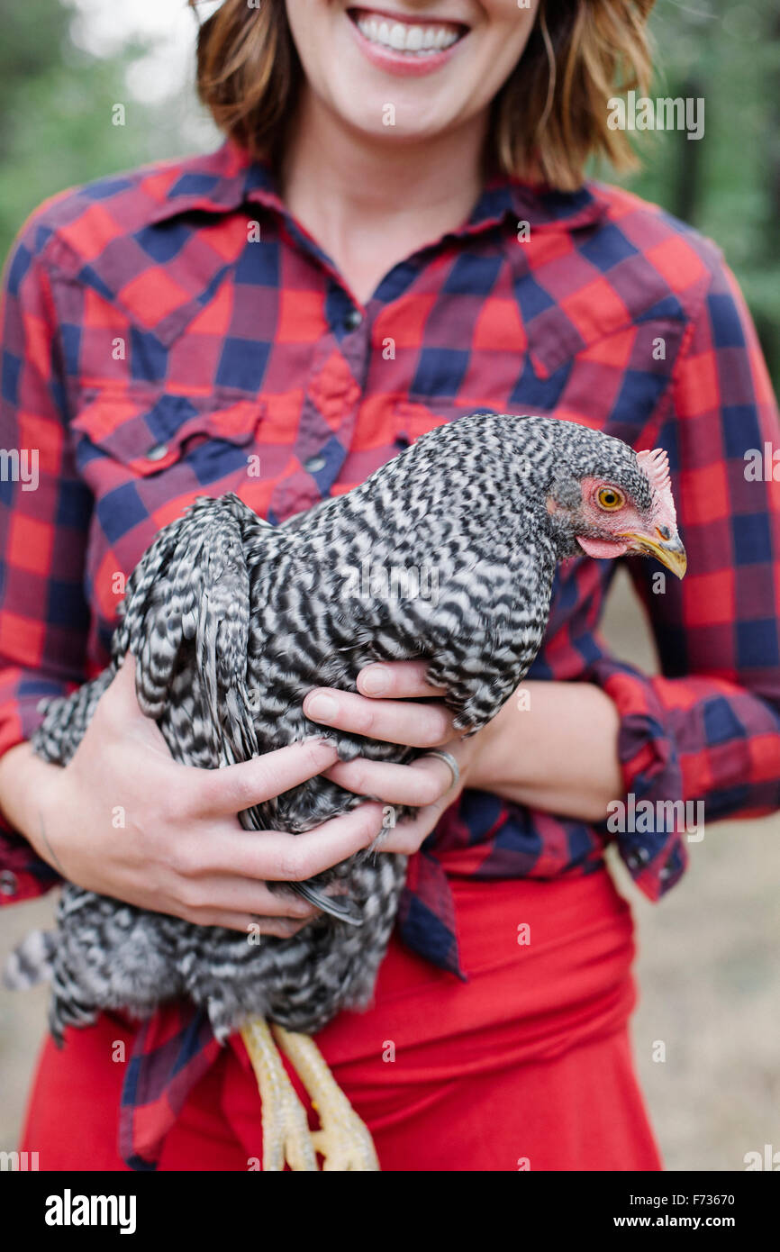 Portrait of a smiling woman holding a grey specked hen Stock Photo - Alamy