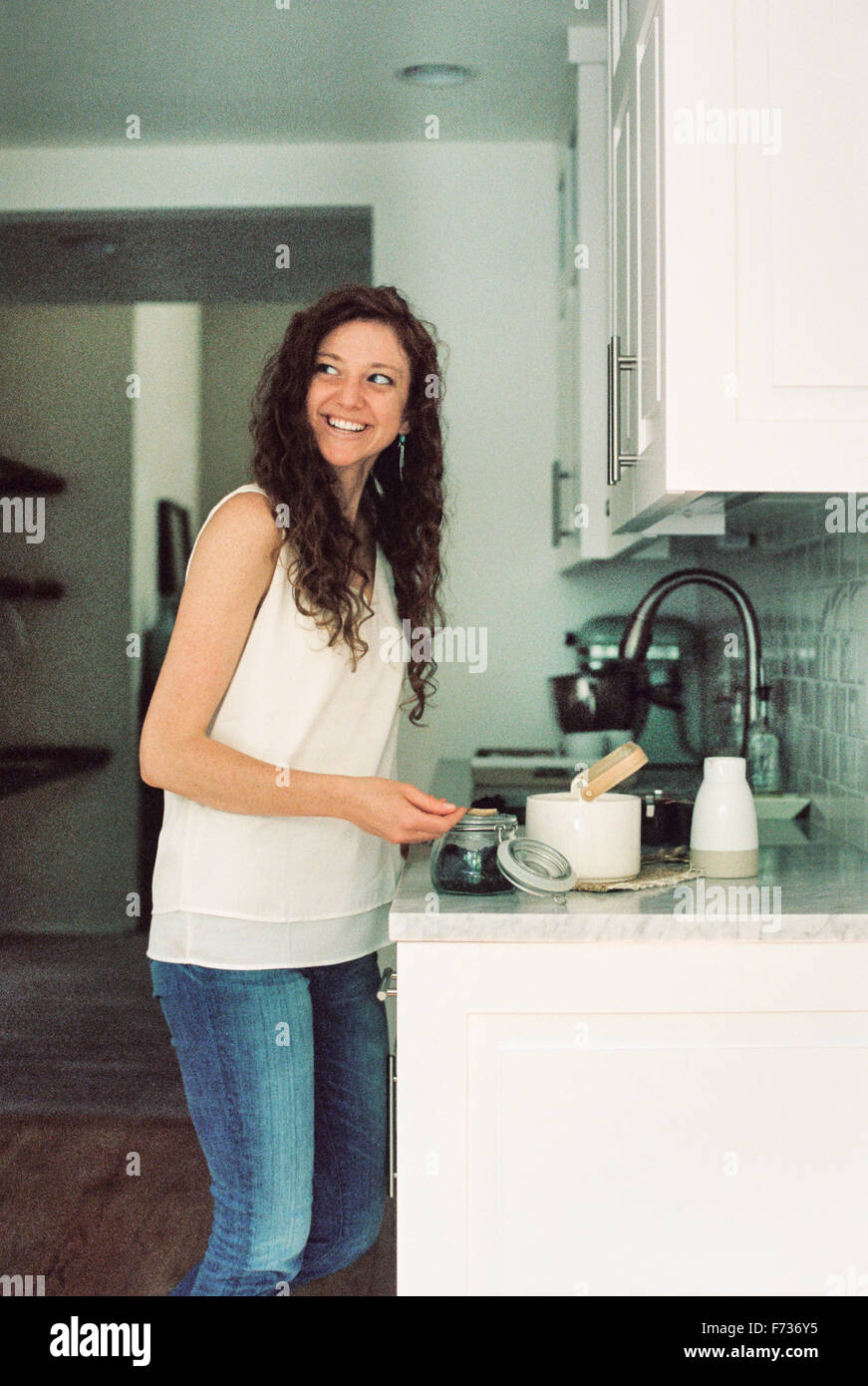 Woman standing in a kitchen preparing a pot of tea Stock Photo - Alamy