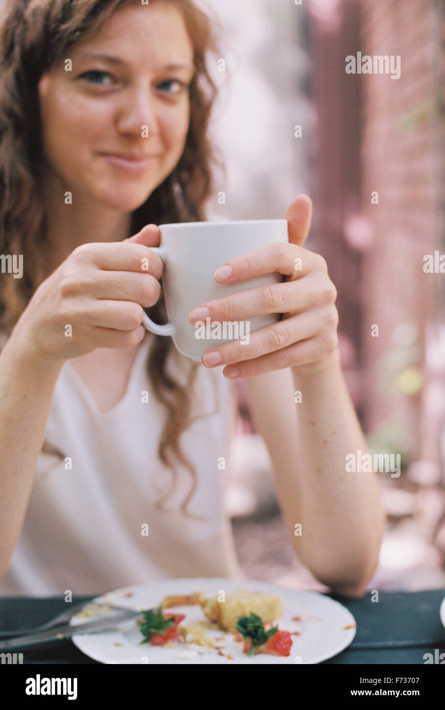 Smiling woman holding a white china teacup Stock Photo - Alamy