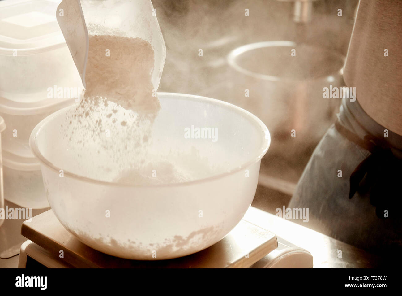 A baker preparing ingredients, using a measuring scale and pouring ...