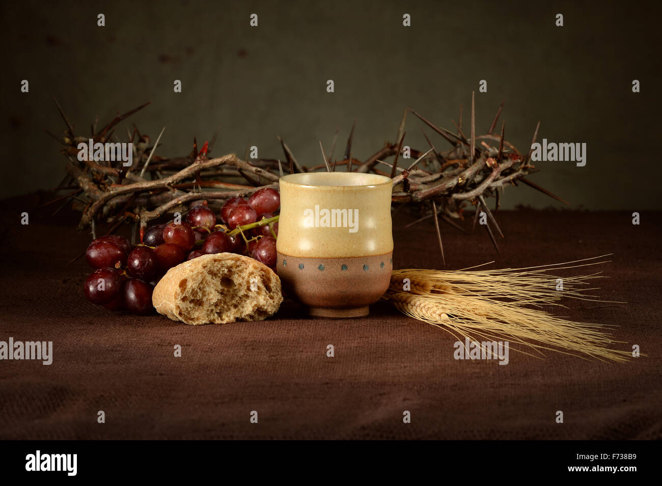 Communion concept with cup of wine, bread, crown of thorns, red grapes ...