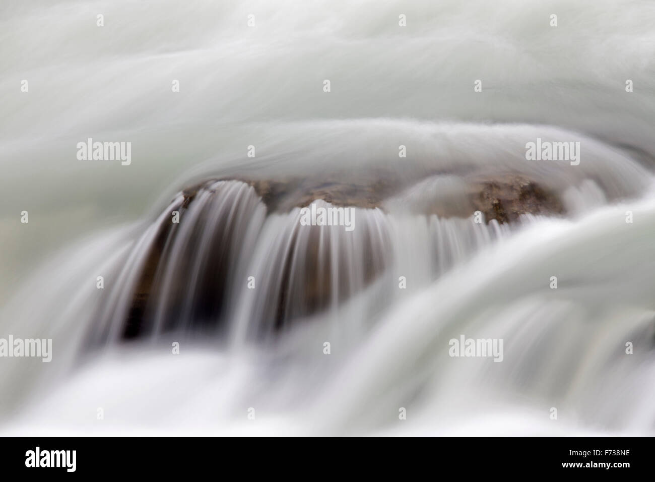 Motion blurred water flowing over boulder in mountain stream Stock ...